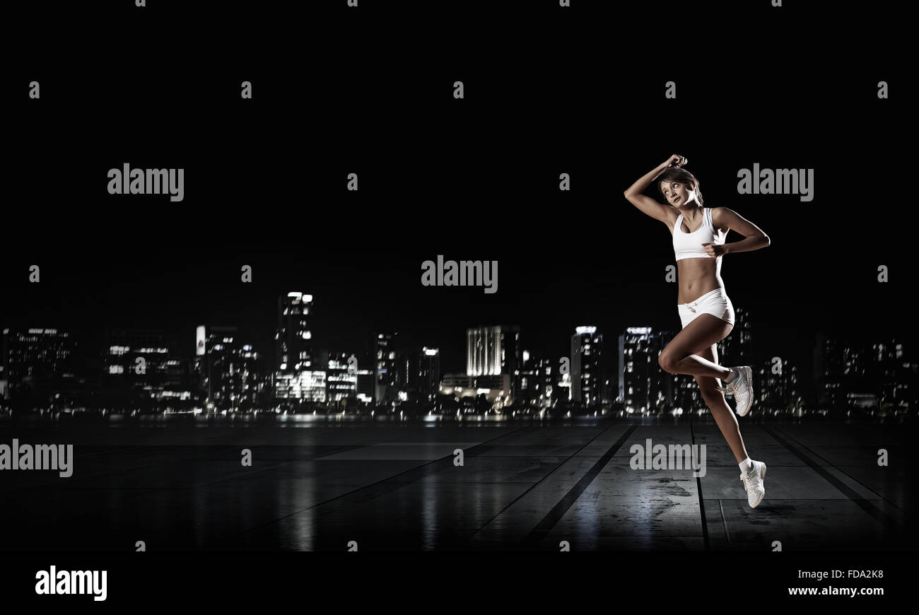Young woman athlete running fast on dark background Stock Photo - Alamy