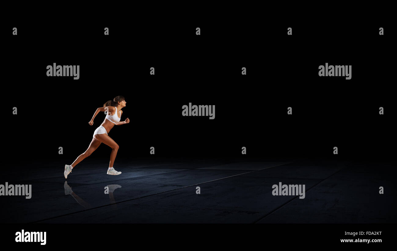 Young woman athlete running fast on dark background Stock Photo - Alamy