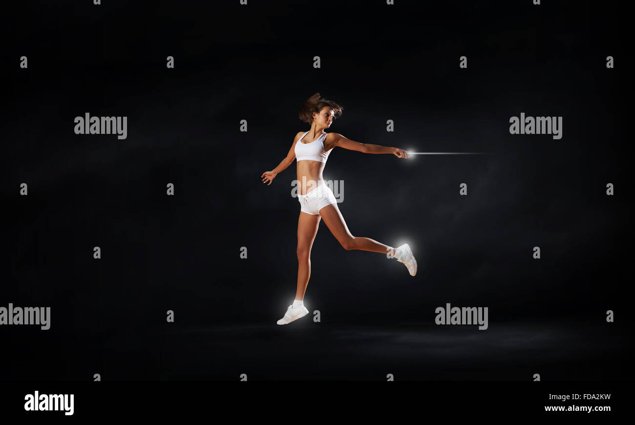 Young woman athlete running fast on dark background Stock Photo - Alamy