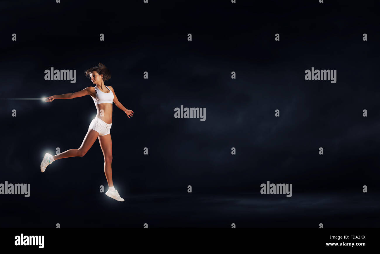 Young woman athlete running fast on dark background Stock Photo - Alamy