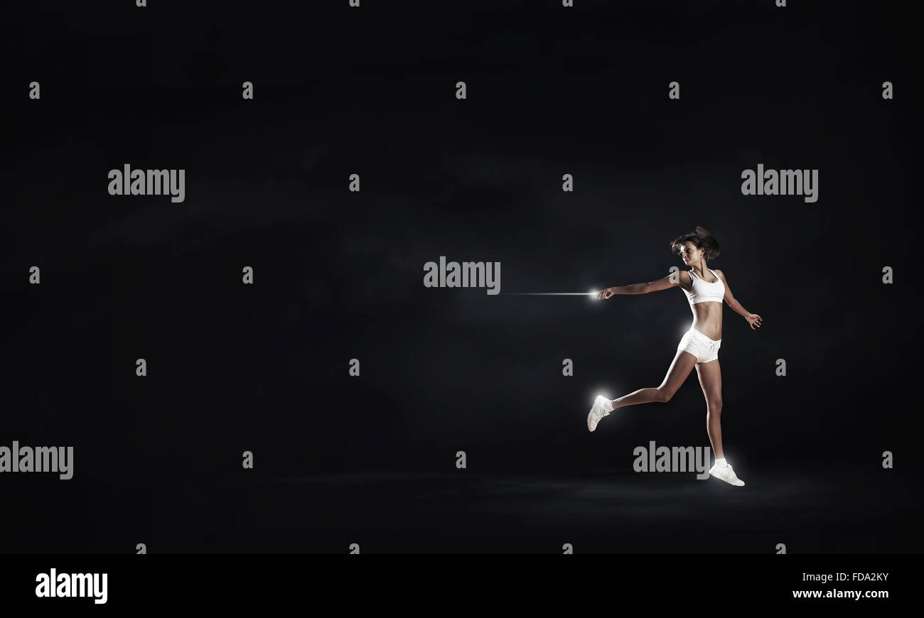 Young woman athlete running fast on dark background Stock Photo - Alamy