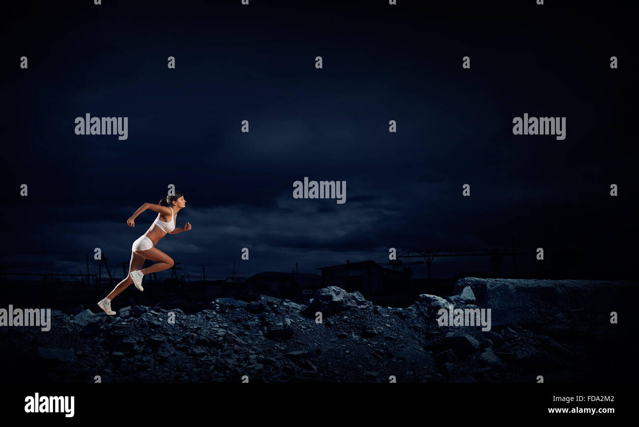 Young woman athlete running fast on dark background Stock Photo - Alamy