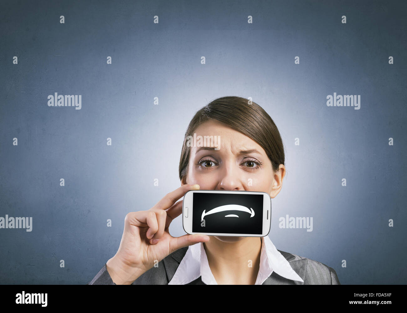 Beautiful young woman holding mobile phone against her mouth and ...