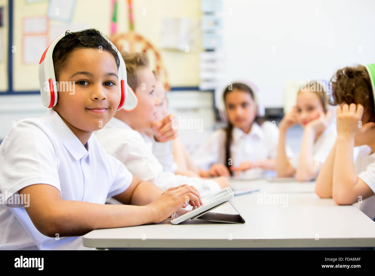 Group of children wearing colourful wireless headsets while working on ...