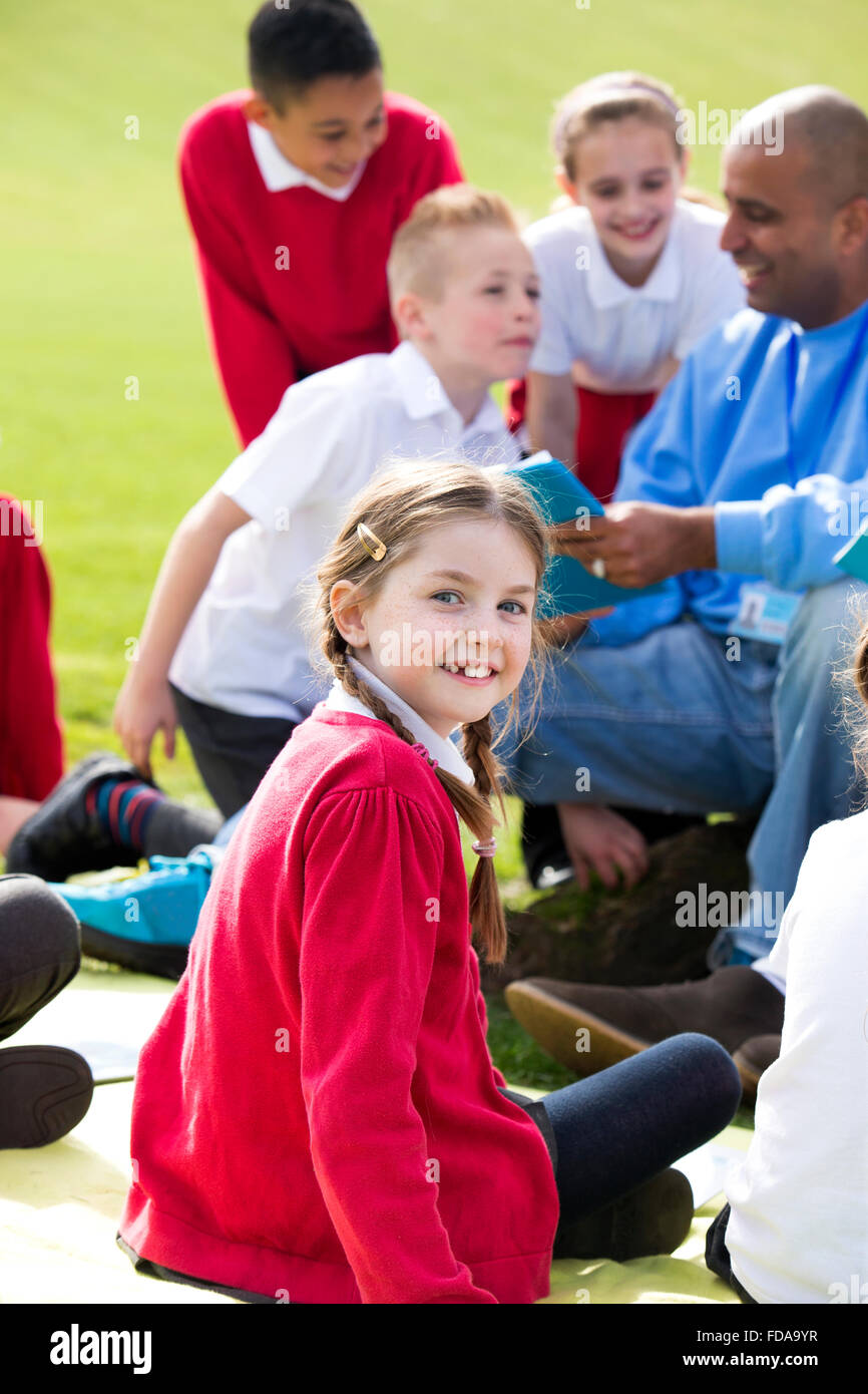 Small group of children sitting on the grass having a lesson outdoors ...