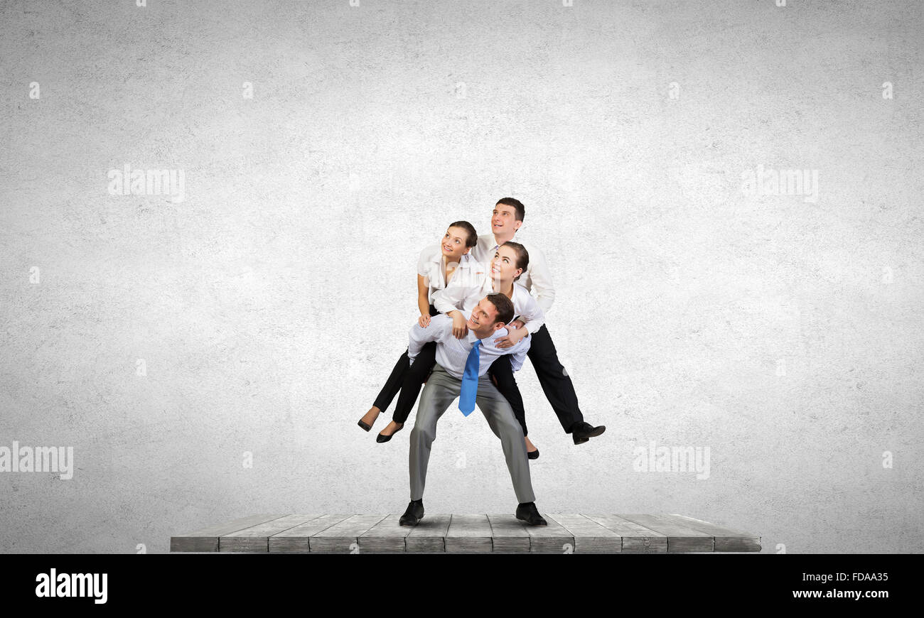 Businesspeople riding on back of their colleague Stock Photo - Alamy