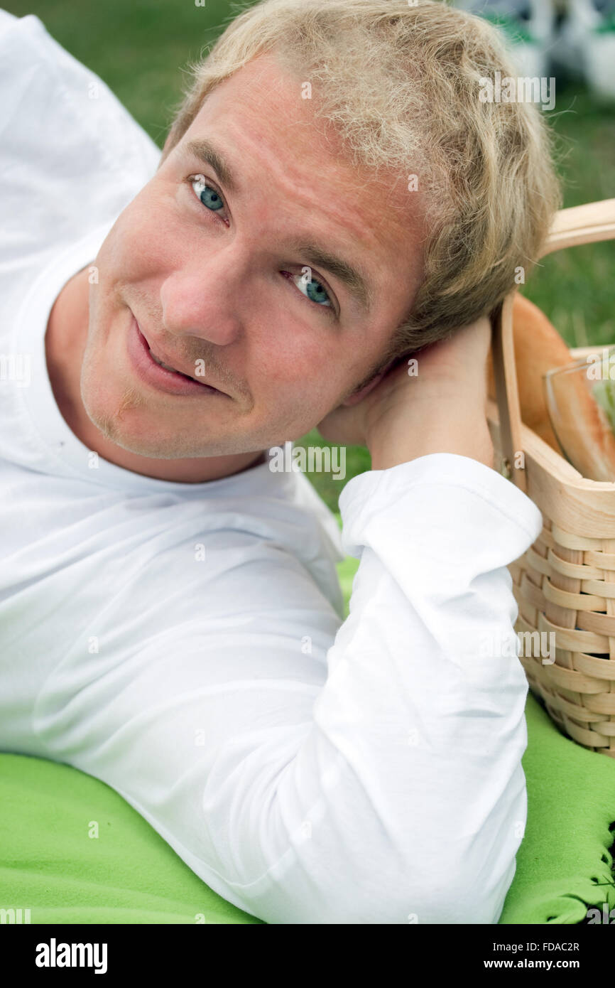 Young smiling man lying down in a picnic setting Stock Photo - Alamy
