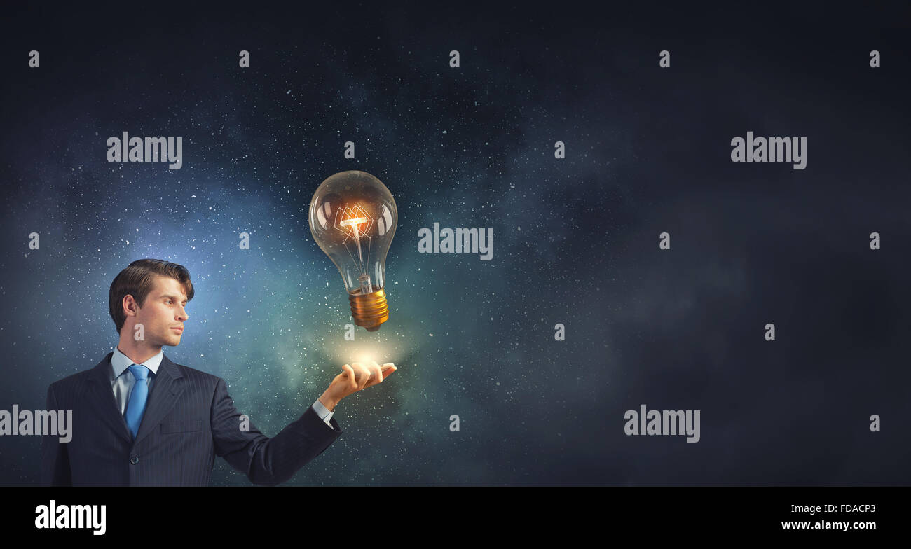 Young businessman and glass glowing light bulb Stock Photo - Alamy