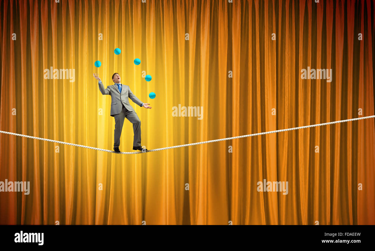 Young businessman balancing on rope and juggling with balls Stock Photo ...