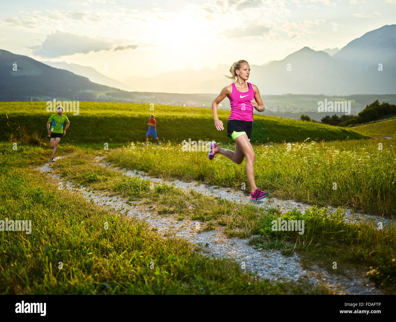 Young woman in her twenties running on path through fields, more ...