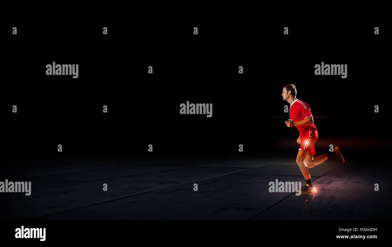 Running man in red sport wear on dark background Stock Photo - Alamy
