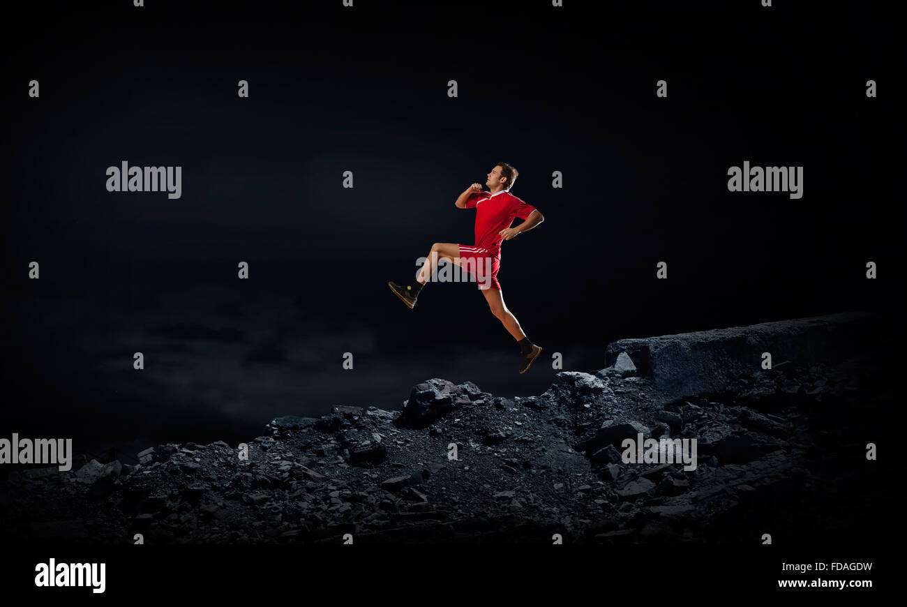 Running man in red sport wear on dark background Stock Photo - Alamy