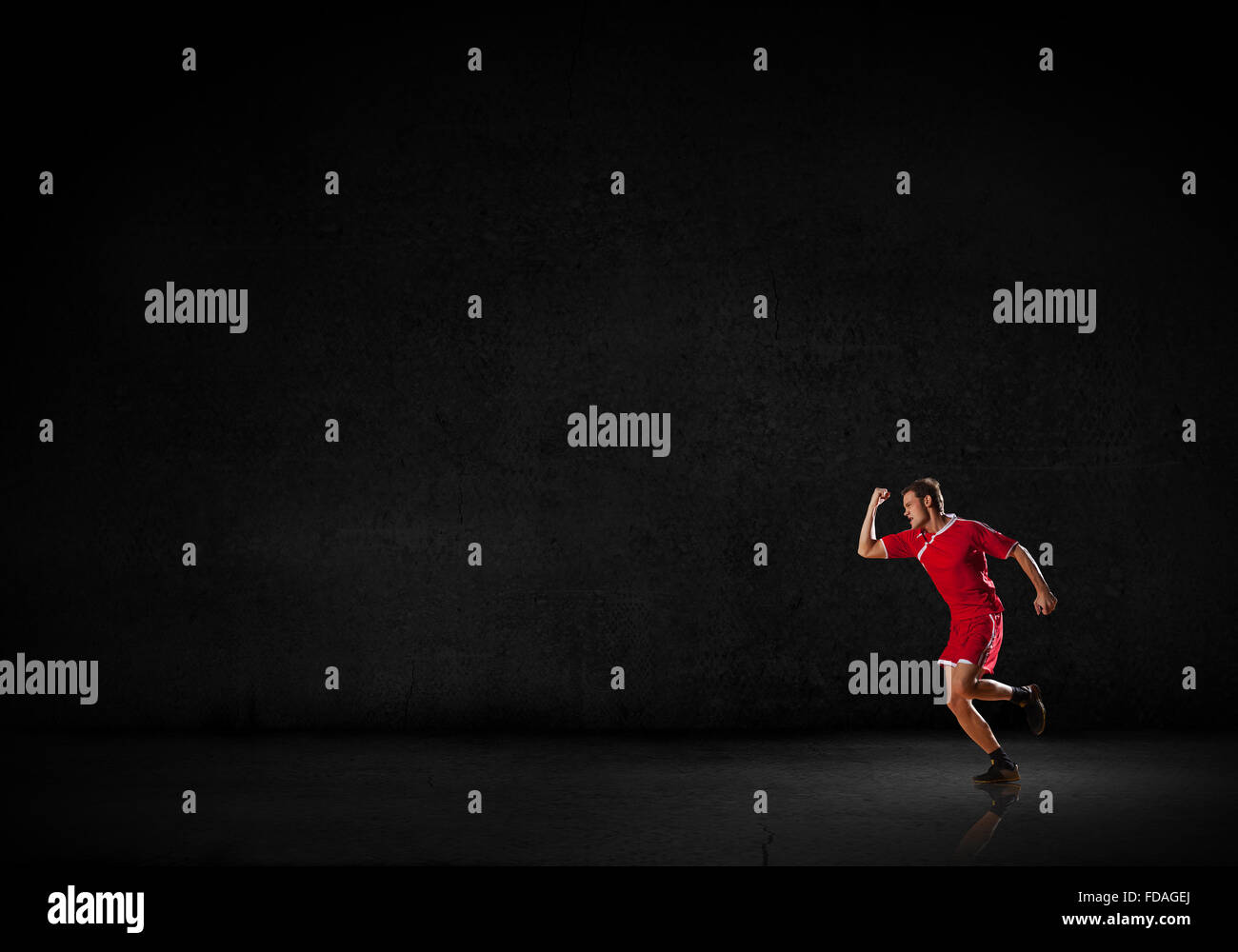 Running man in red sport wear on dark background Stock Photo - Alamy