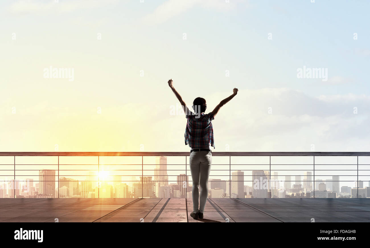 Back view of cheerful woman with hands up facing sunrise Stock Photo ...