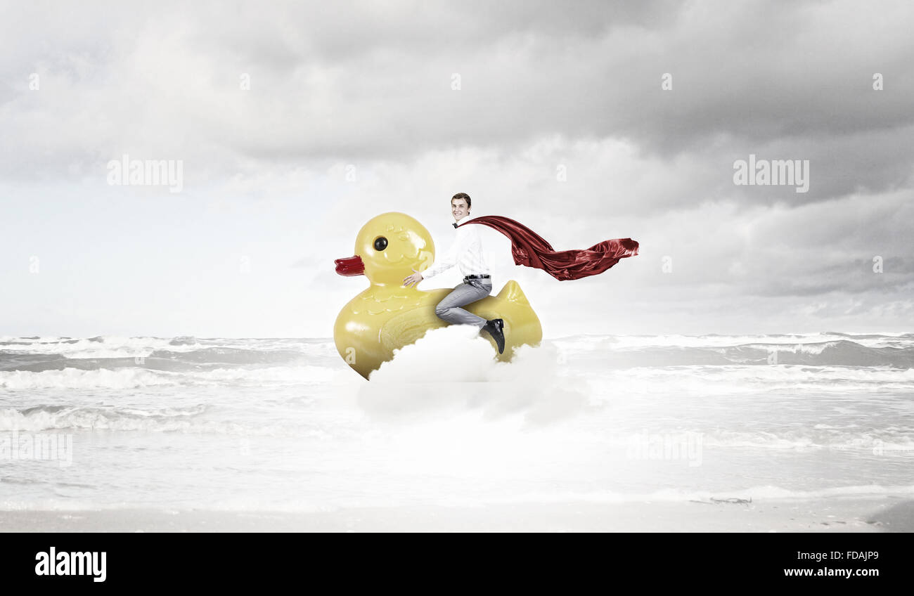 Young happy businessman riding yellow rubber duck Stock Photo - Alamy