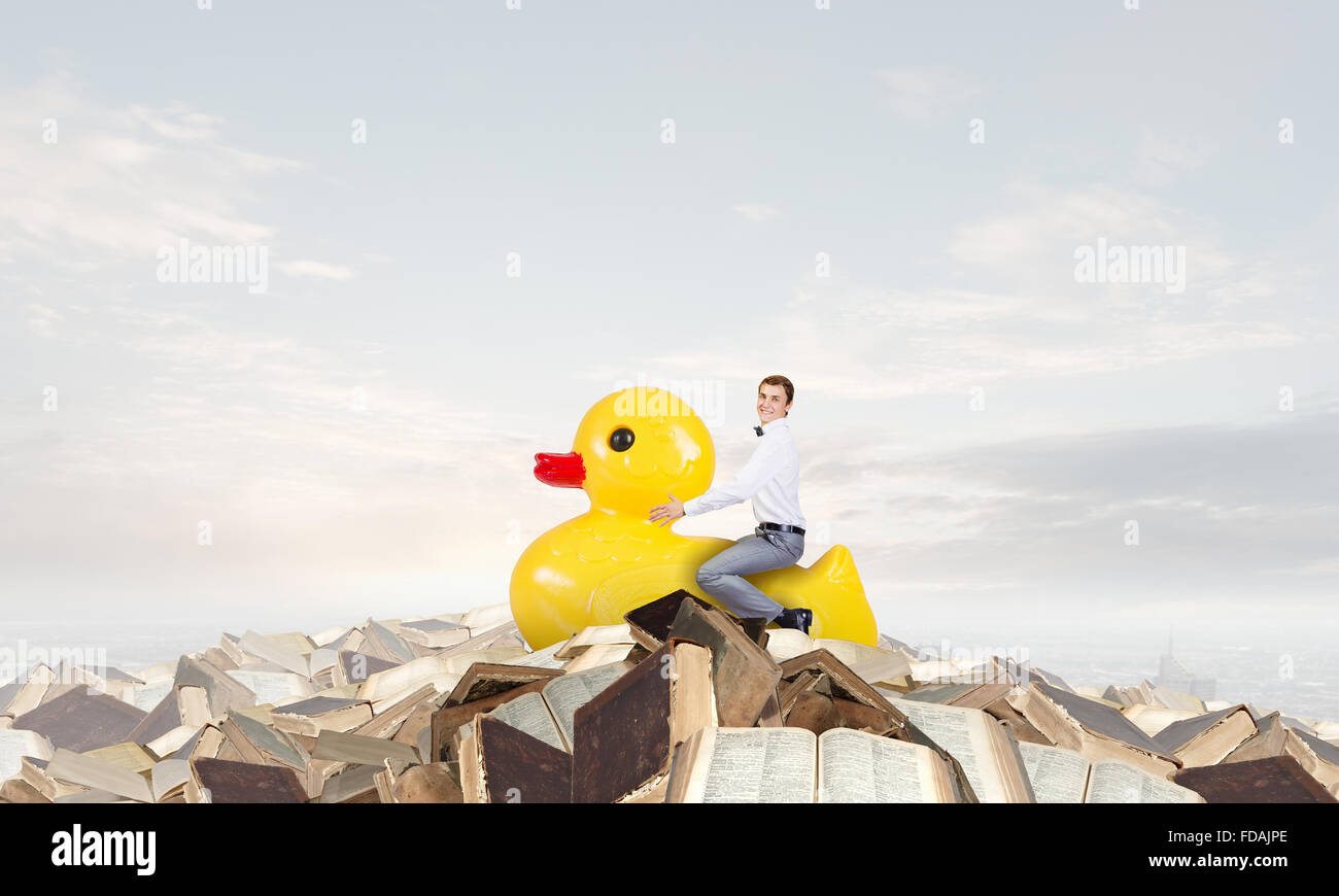 Young happy businessman riding yellow rubber duck Stock Photo - Alamy