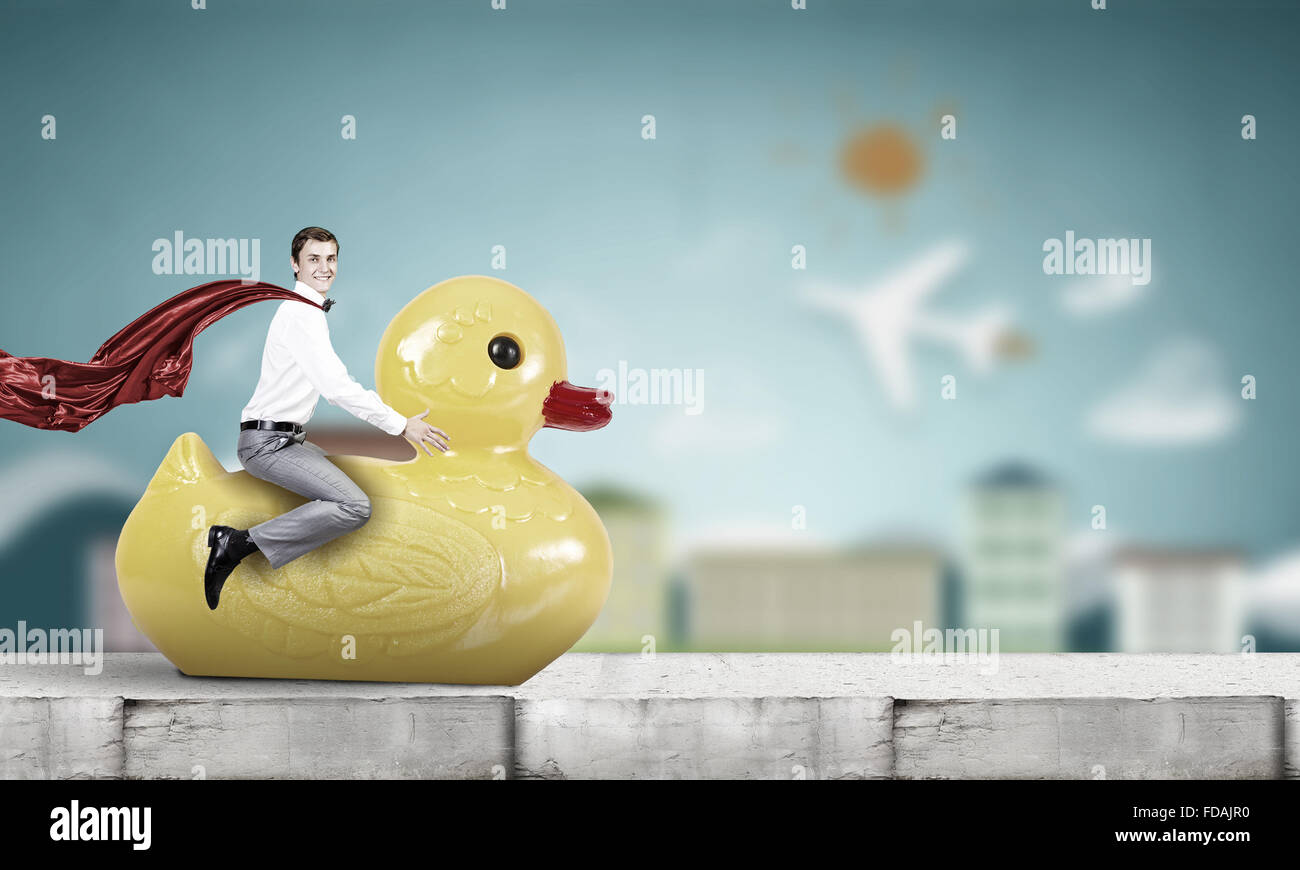 Young happy businessman riding yellow rubber duck Stock Photo - Alamy