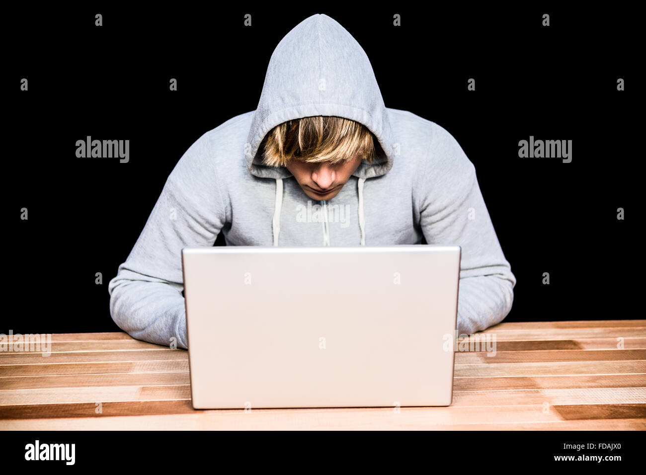 Man in hood jacket hacking a laptop Stock Photo - Alamy