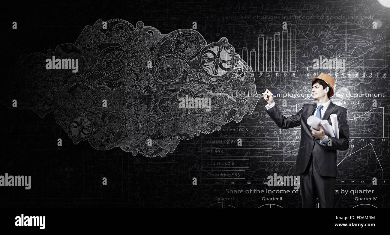 Young man engineer in helmet drawing gears mechanism Stock Photo - Alamy