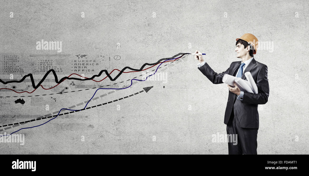 Young man engineer in helmet drawing increasing graph Stock Photo - Alamy