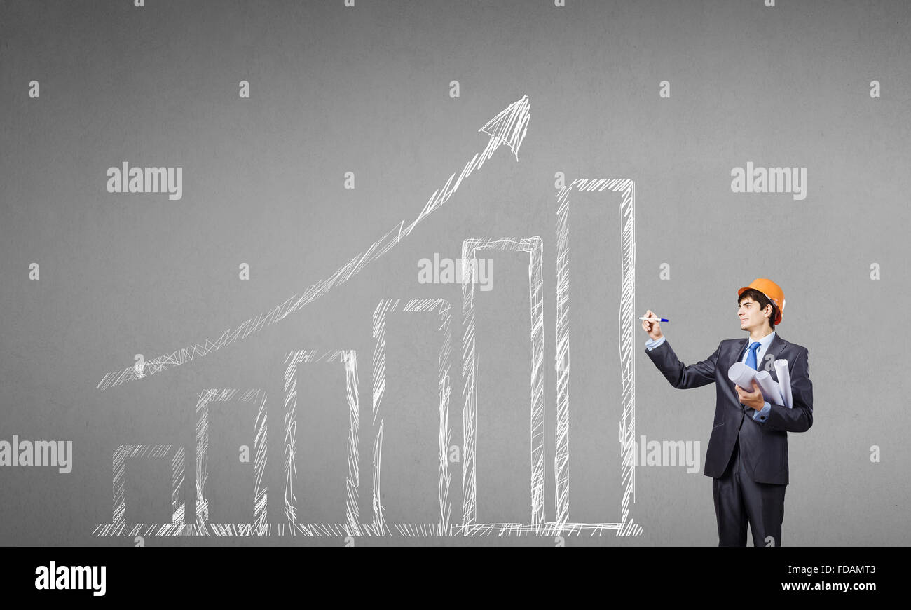 Young man engineer in helmet drawing increasing graph Stock Photo - Alamy
