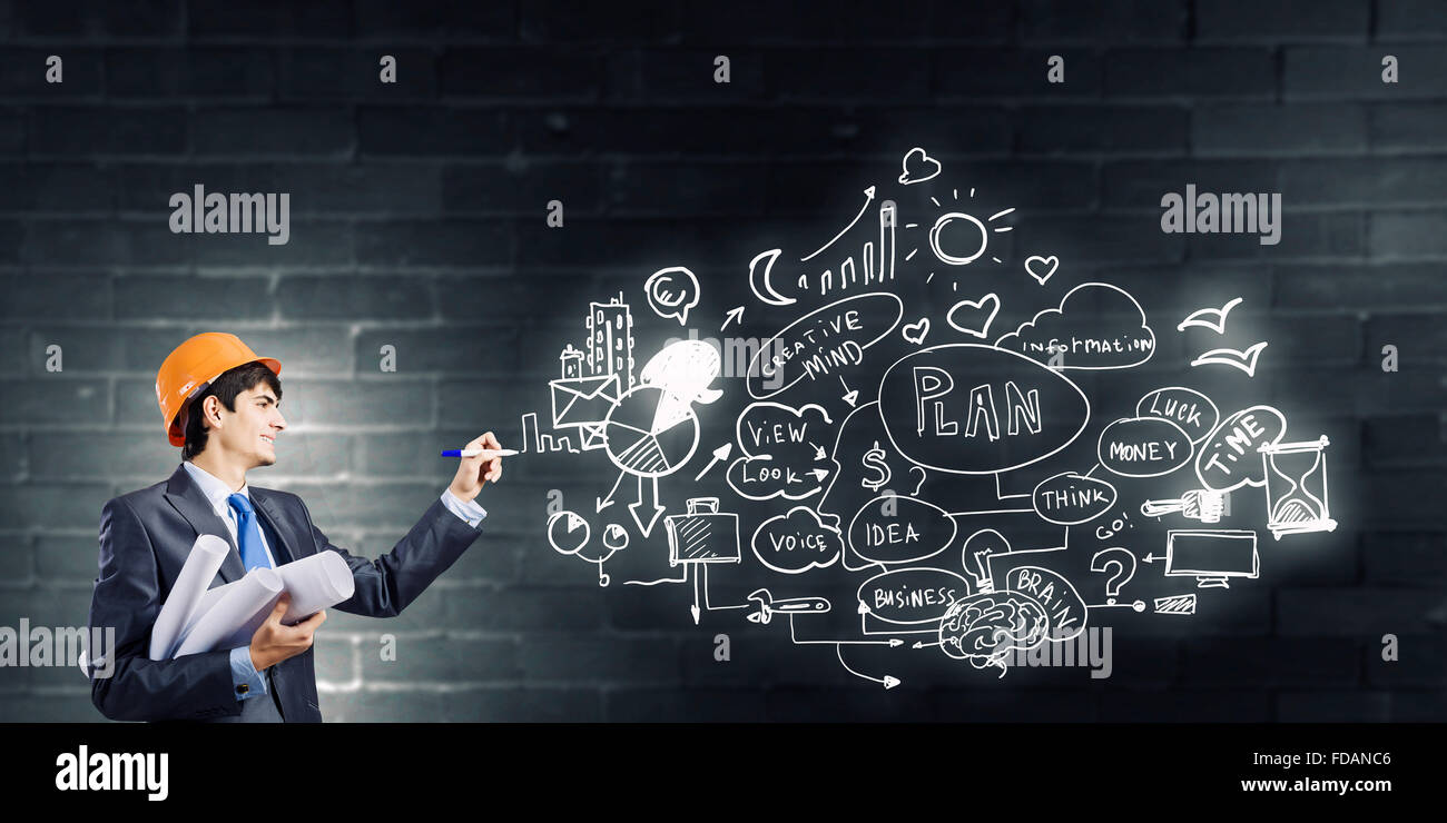 Young man engineer in helmet drawing plan Stock Photo - Alamy