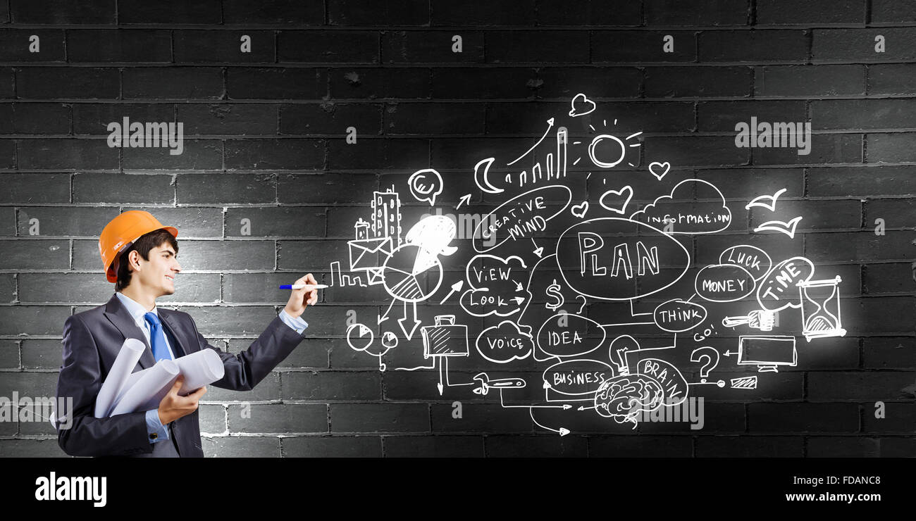 Young man engineer in helmet drawing plan Stock Photo - Alamy