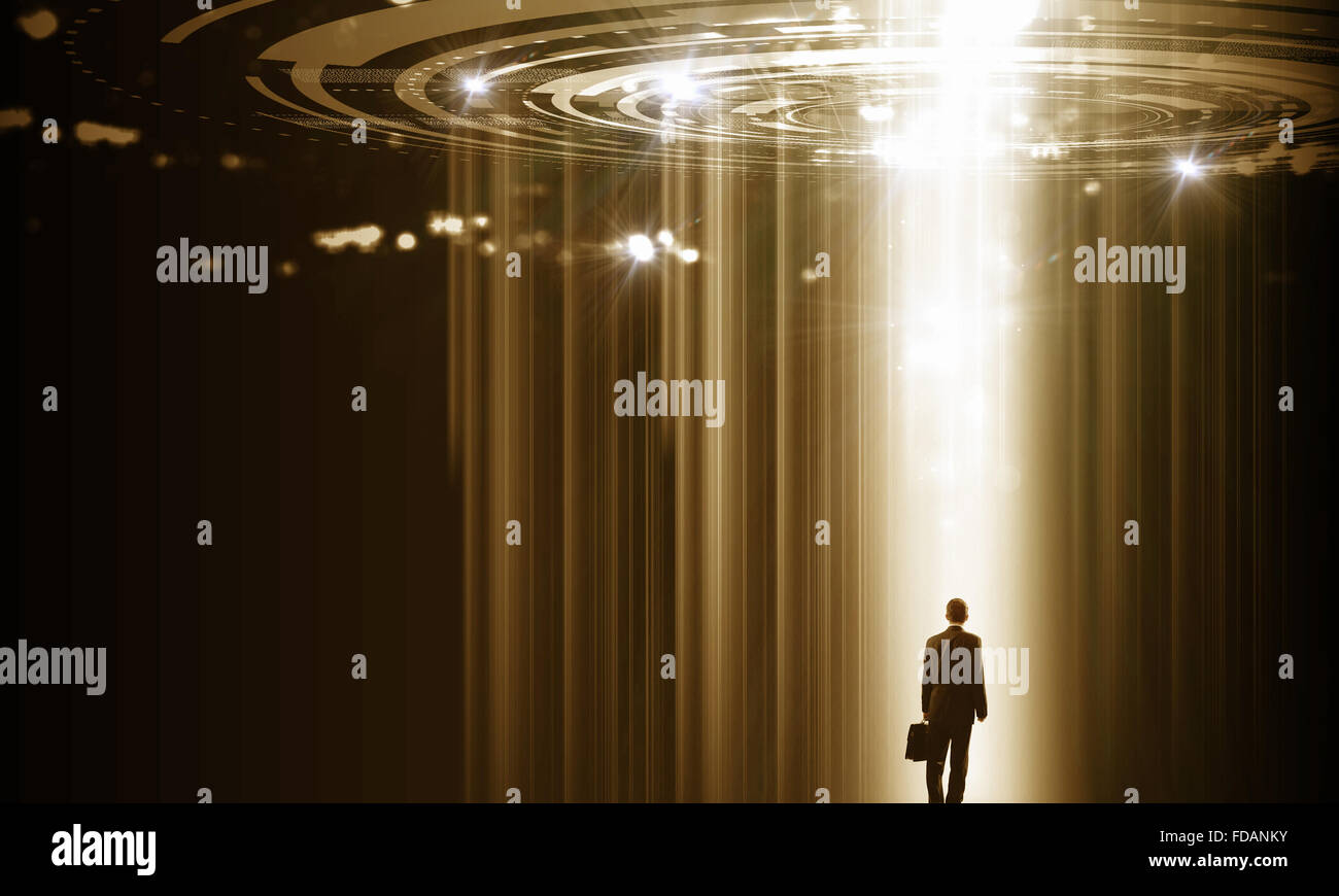 Rear view of businessman standing in light going from above Stock Photo ...