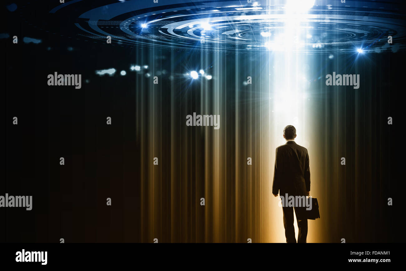 Rear view of businessman standing in light going from above Stock Photo ...