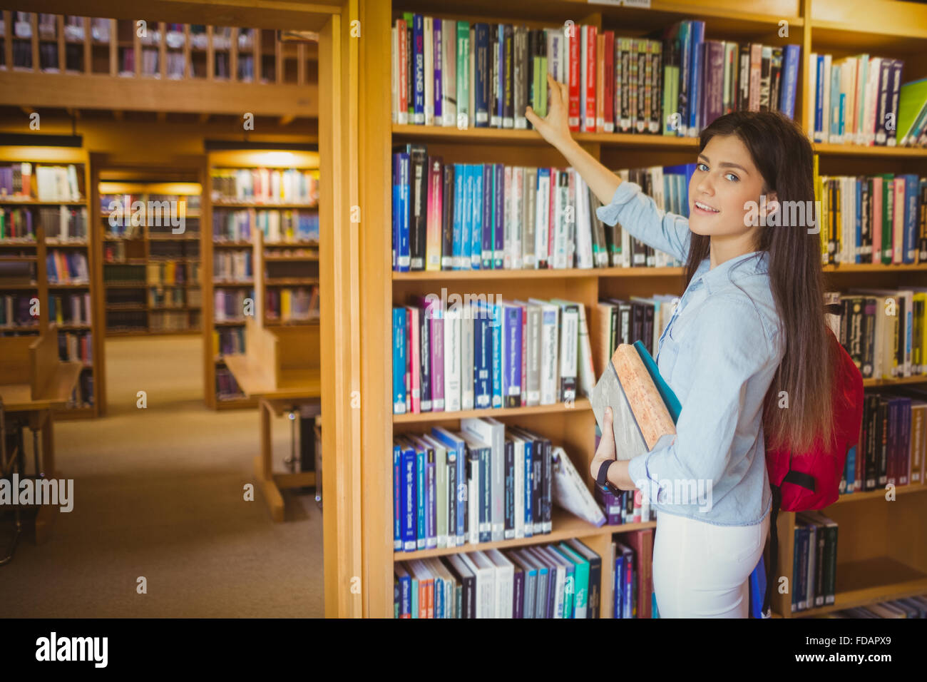 Smiling brunette student picking out book Stock Photo - Alamy