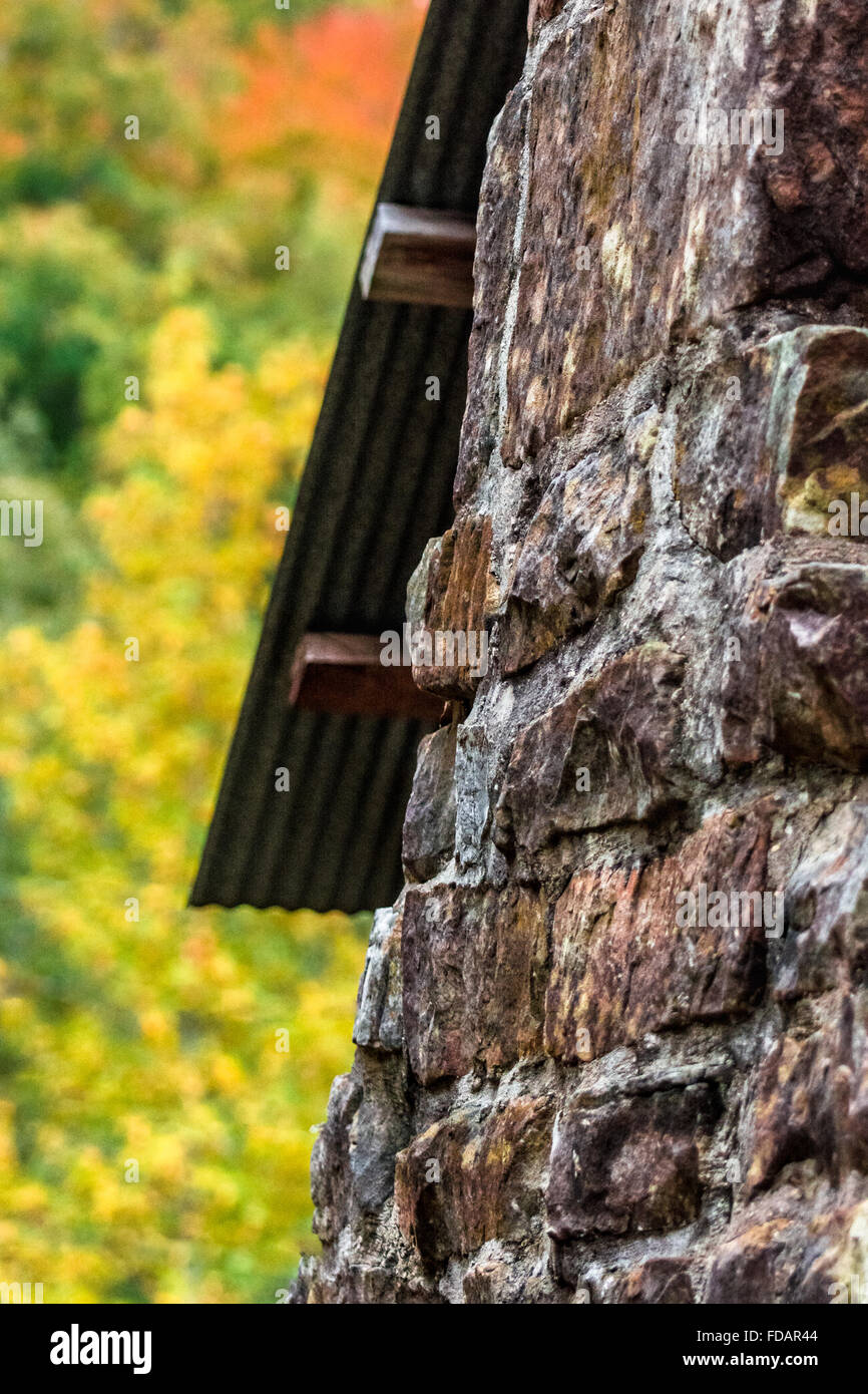 Closeup side view of a rock chimney with fall colors in the back ground ...