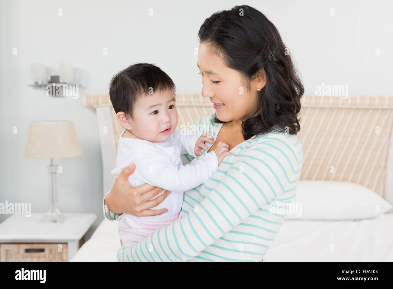 Smiling mother carrying baby daughter Stock Photo - Alamy