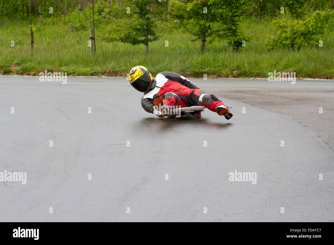 Downhill skateboarder in motorbike leathers and full face helmet ...