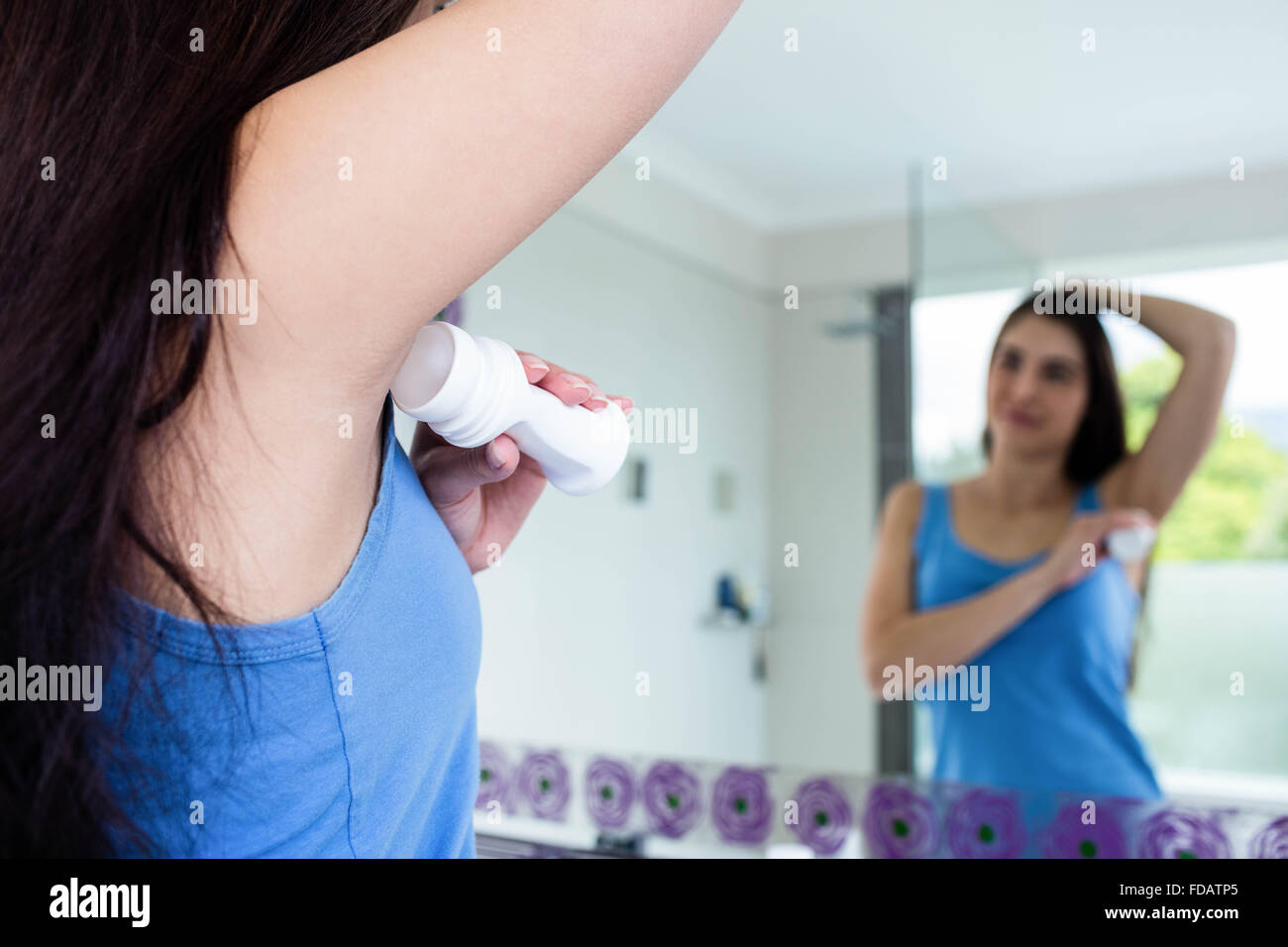 Smiling brunette putting deodorant on her armpit Stock Photo - Alamy