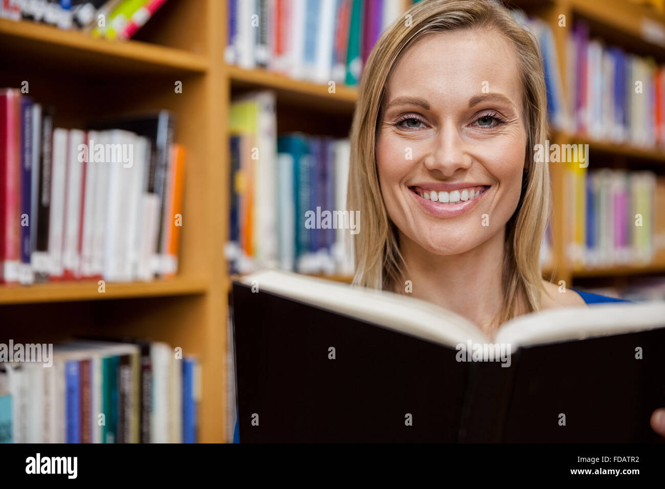 Happy female student reading a book in the library Stock Photo - Alamy
