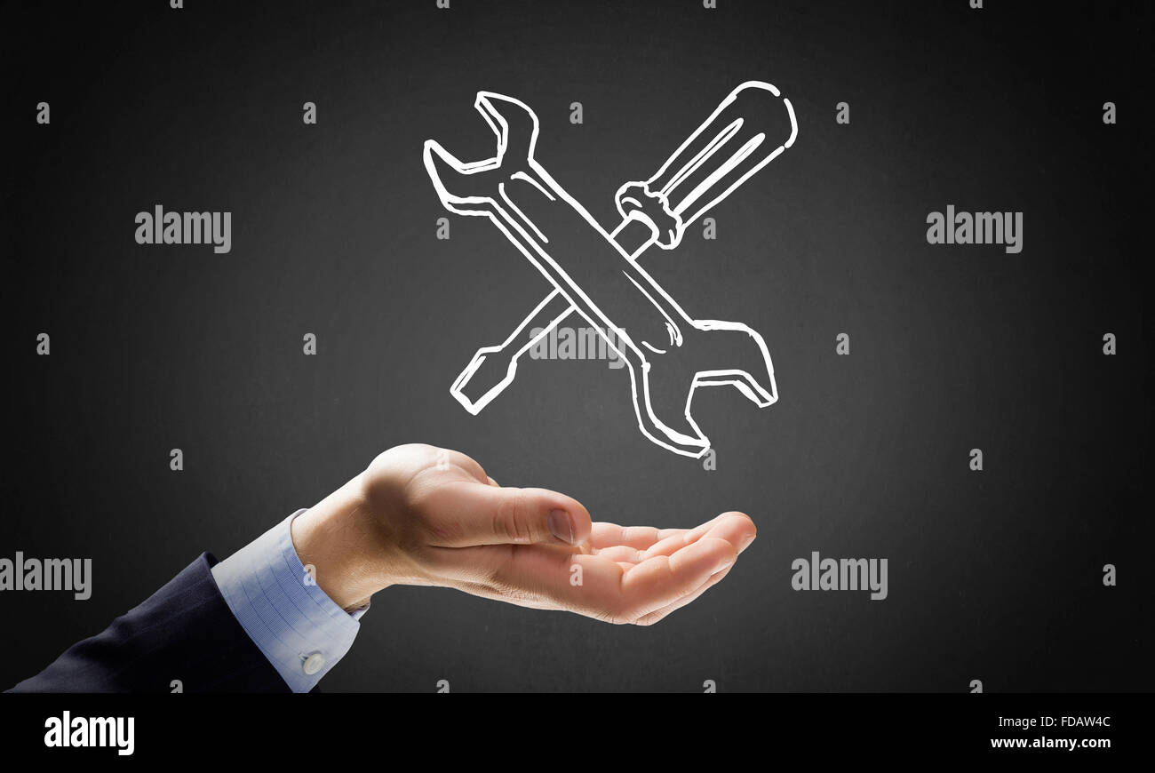 Businessman's hand holding tools over gray background Stock Photo - Alamy