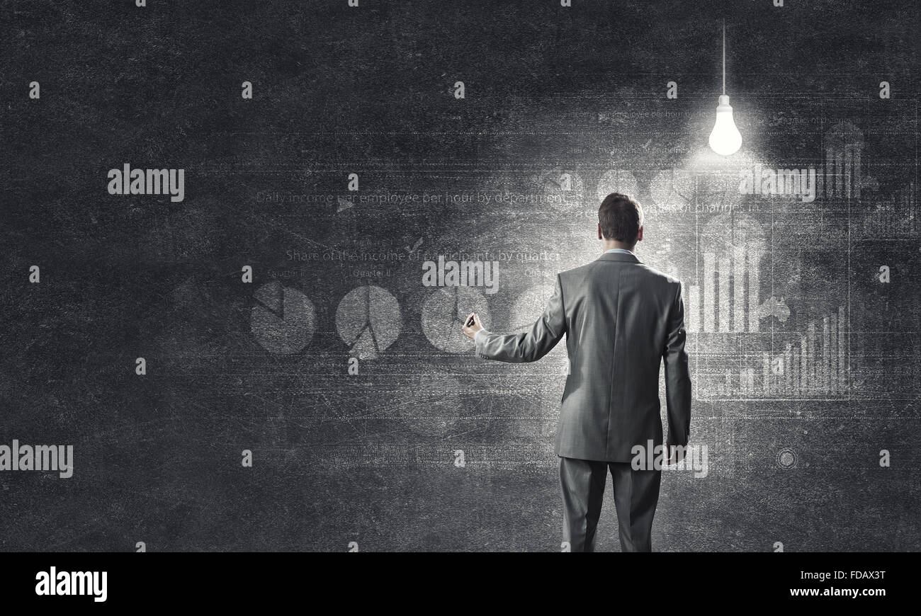 Rear view of businessman drawing marketing charts and graphs Stock ...
