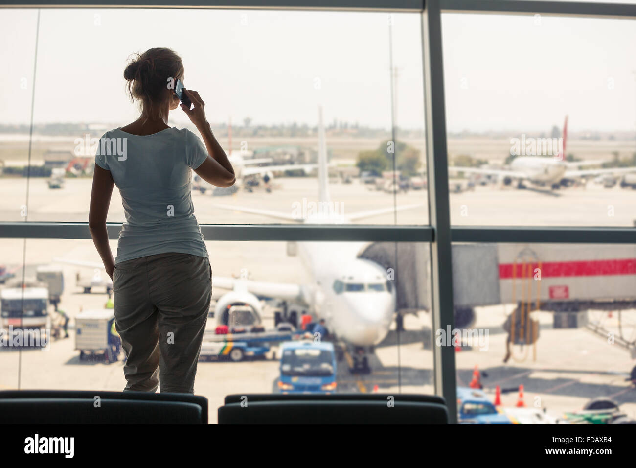 Pretty, young woman waiting at a gate area of a modern airport for the ...