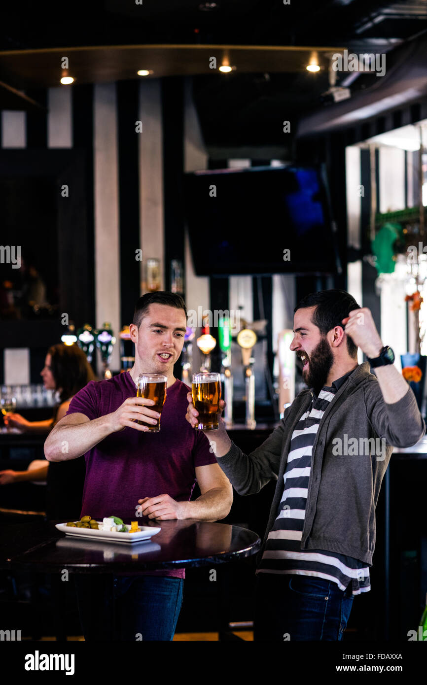 Friends having a pint and cheering Stock Photo - Alamy