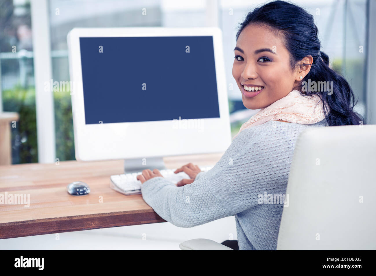 Smiling Asian woman using computer looking back at the camera Stock ...