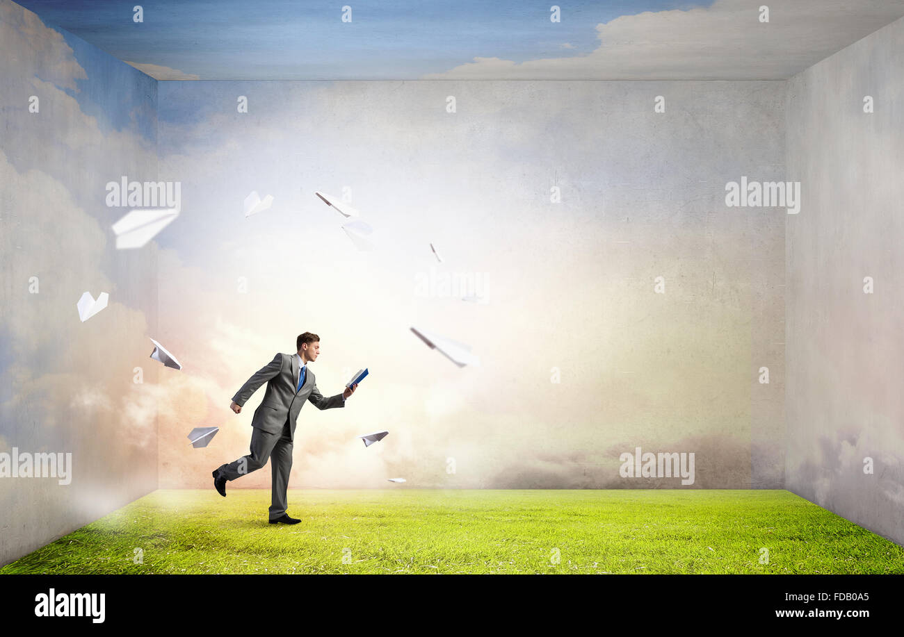 Young businessman running with book in hand Stock Photo - Alamy