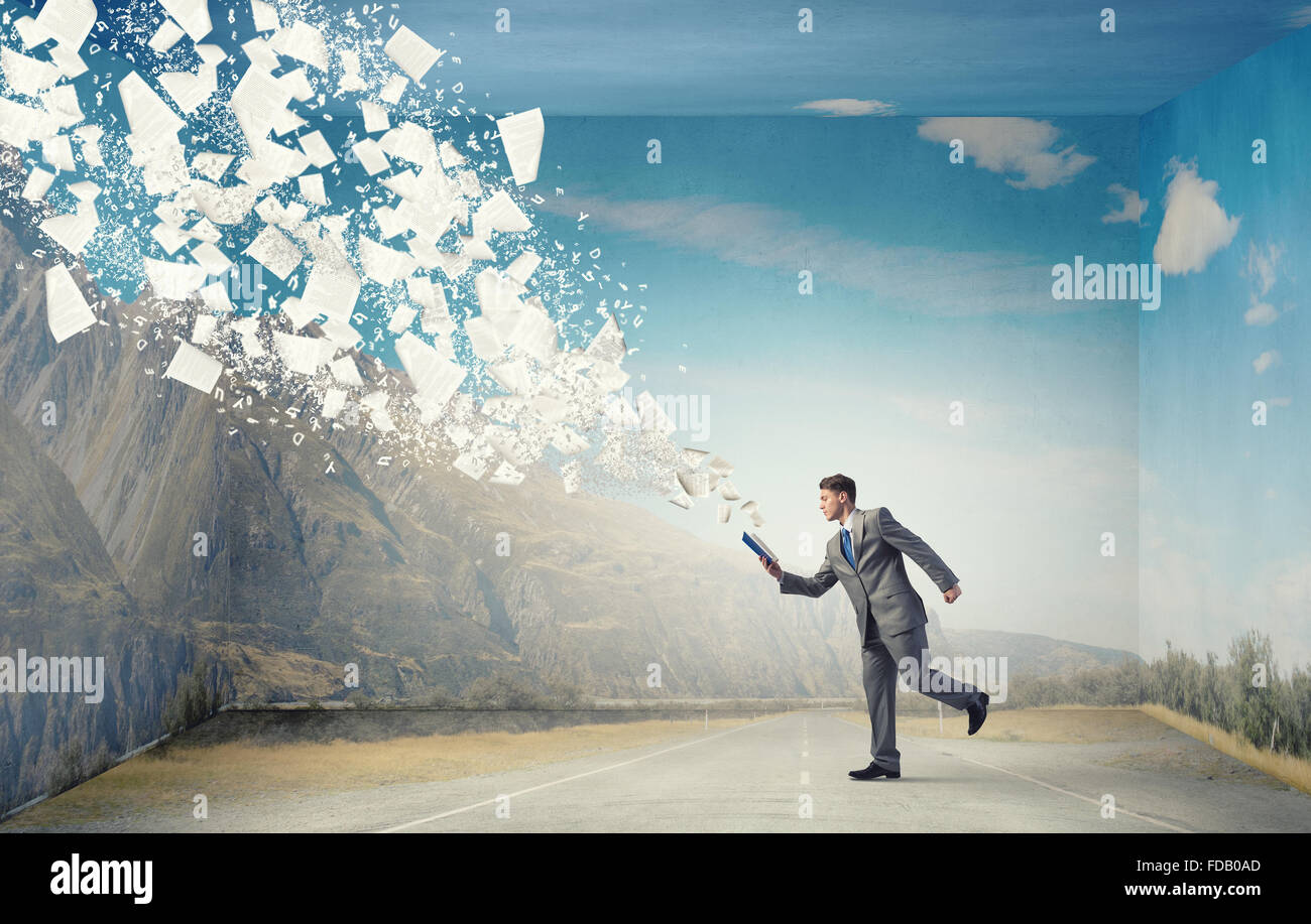 Young businessman running with book in hand Stock Photo - Alamy