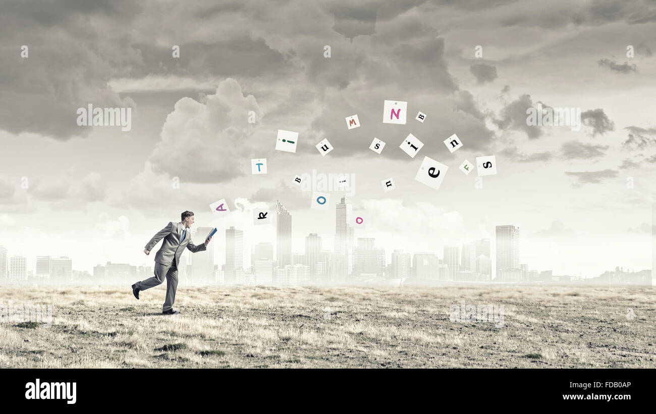 Young businessman running with book in hand Stock Photo - Alamy