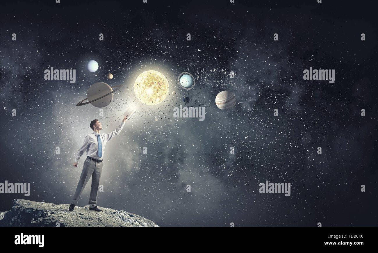 Young man with book exploring planets of sun system Stock Photo - Alamy