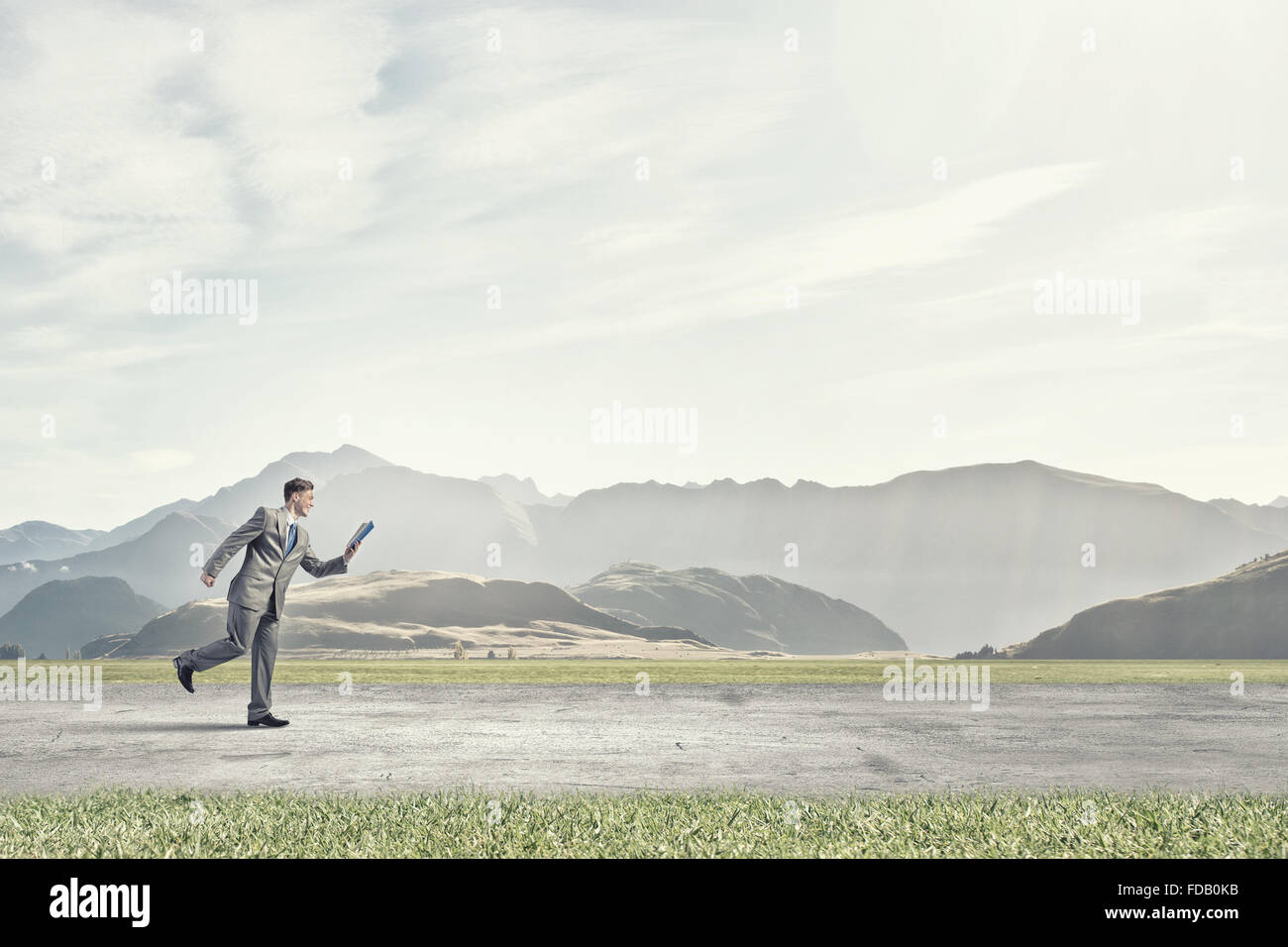 Young businessman running with book in hand Stock Photo - Alamy