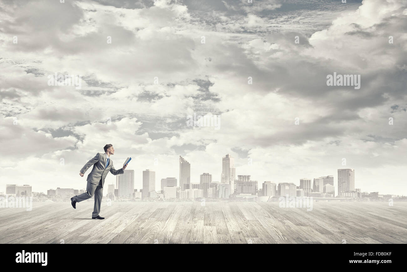 Young businessman running with book in hand Stock Photo - Alamy