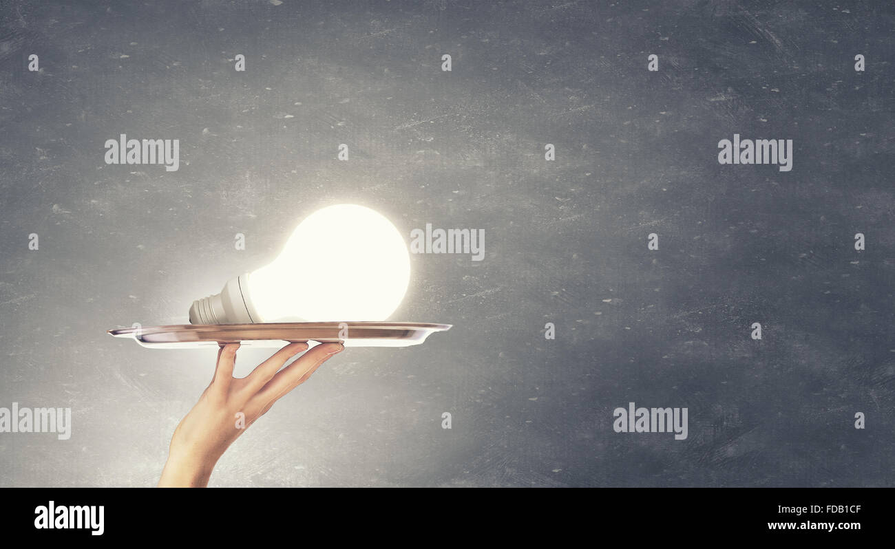 Hand holding tray with glowing light bulb Stock Photo - Alamy