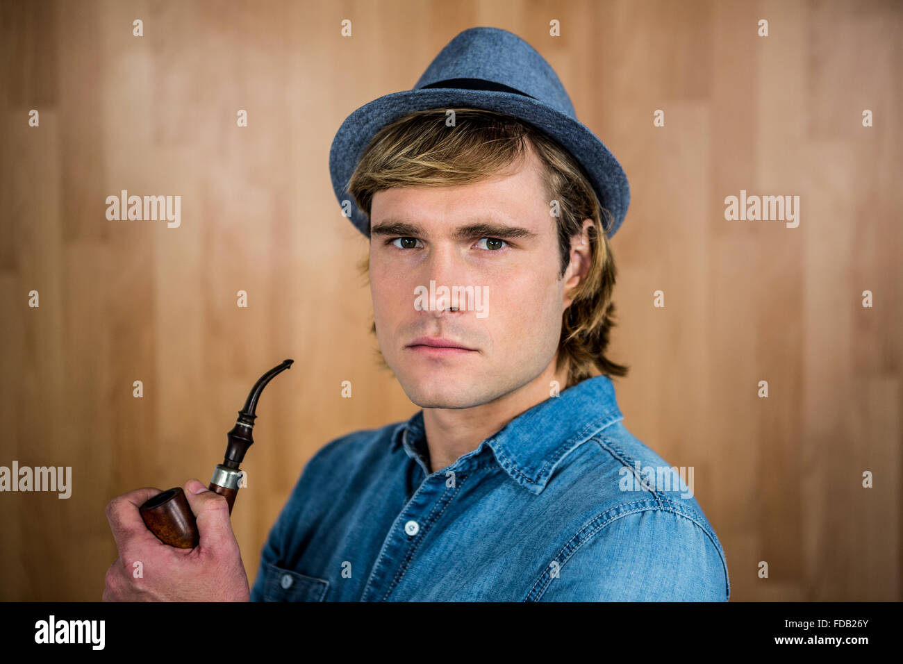 Serious hipster holding pipe Stock Photo - Alamy