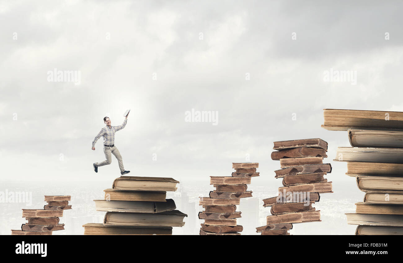 Full length of student running with book in hand Stock Photo - Alamy