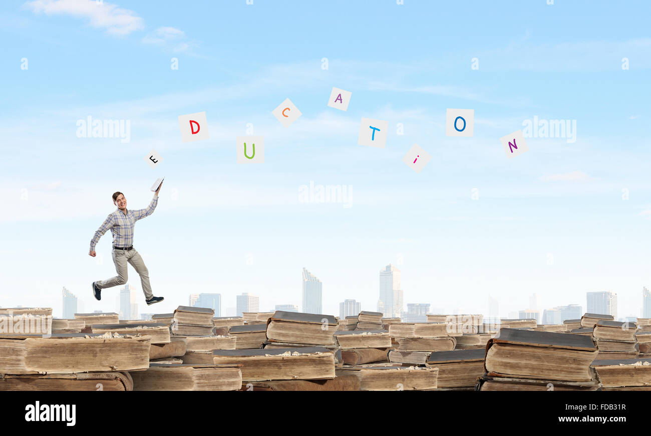 Full length of student running with book in hand Stock Photo - Alamy